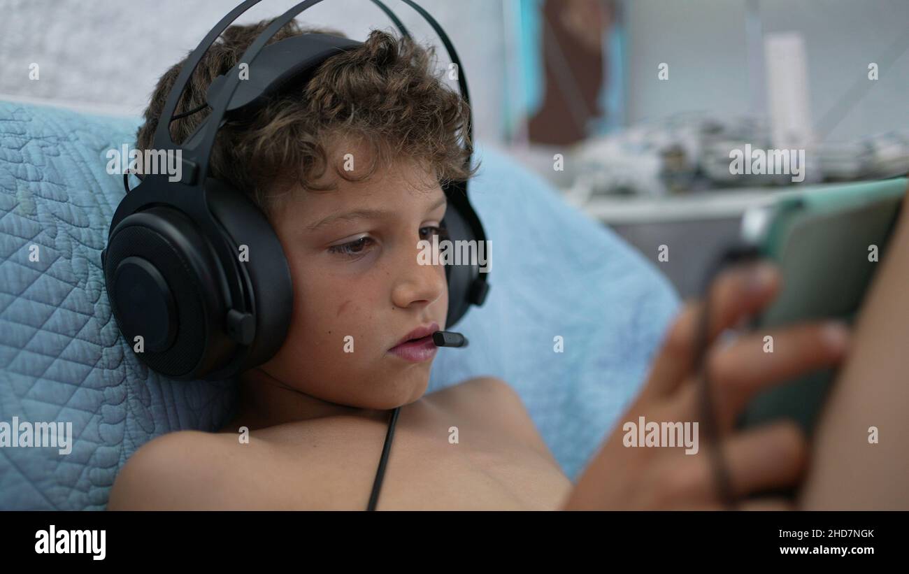 Child plays video-game wearing headset with mic connected online gaming ...