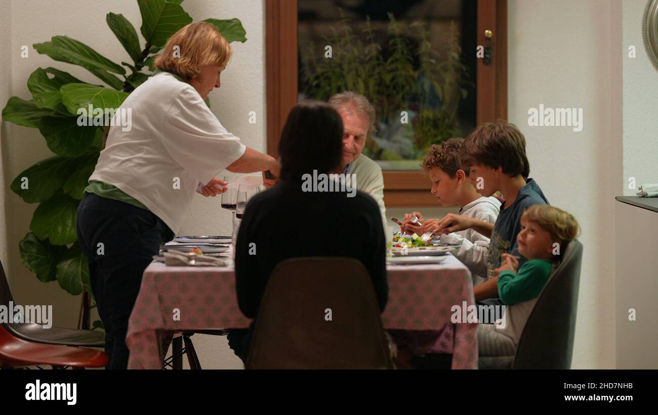 Family eating meal together, grand-parents and children at dinner table ...
