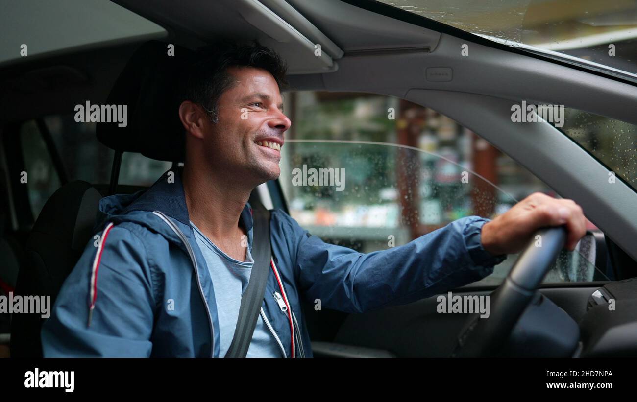 Happy driver holding steering wheel driving in city Stock Photo - Alamy