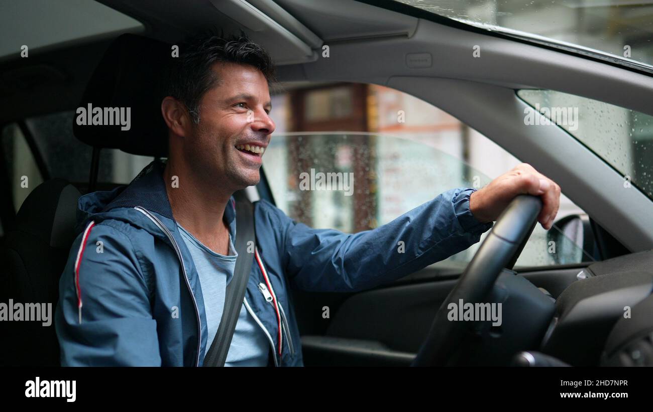 Happy driver holding steering wheel driving in city Stock Photo - Alamy