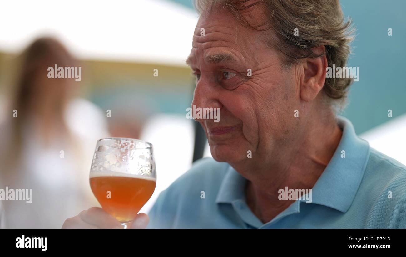 Happy senior man drinking beer with friends in conversation Stock Photo ...