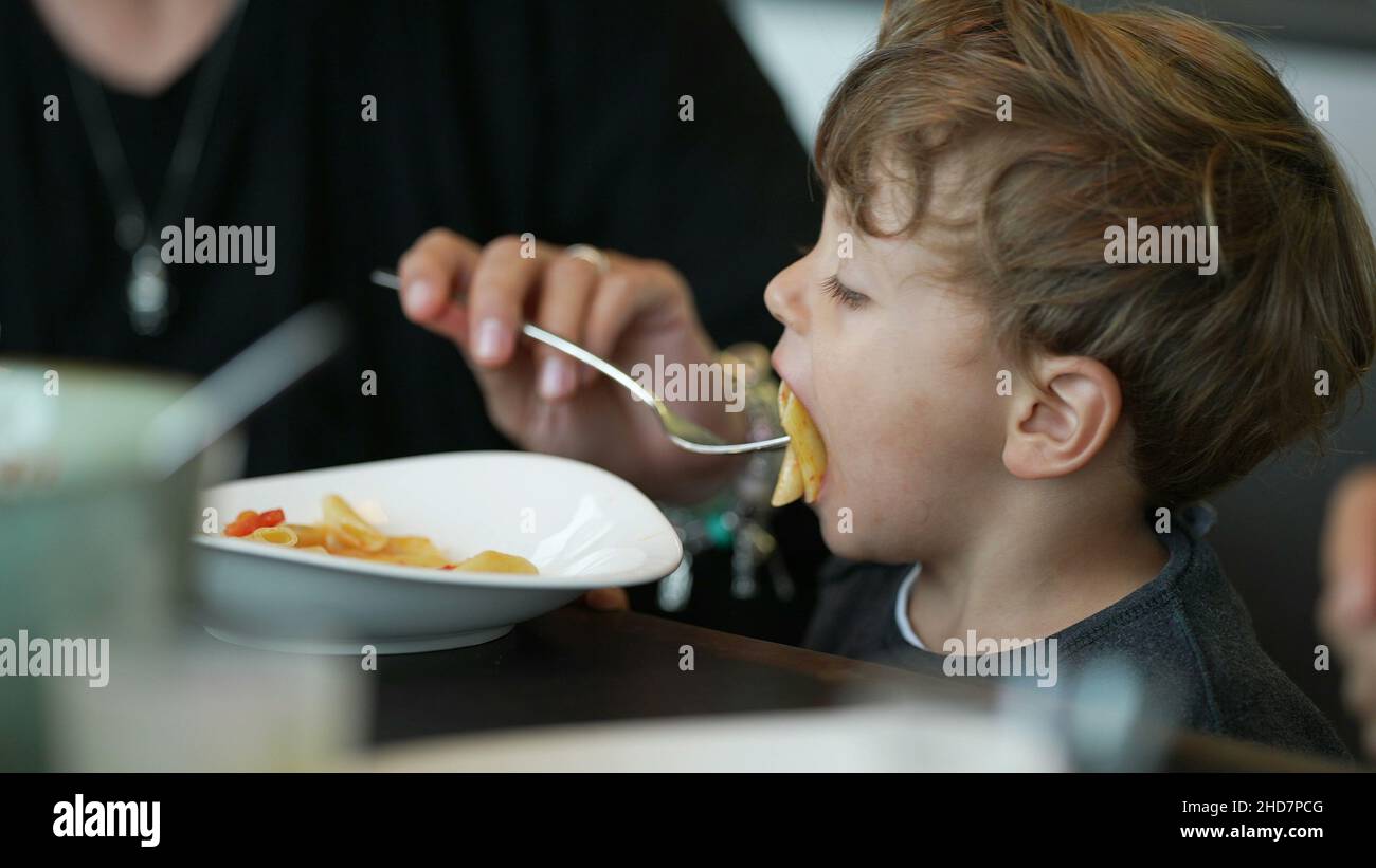 Mother feeding child pasta for lunch Stock Photo - Alamy