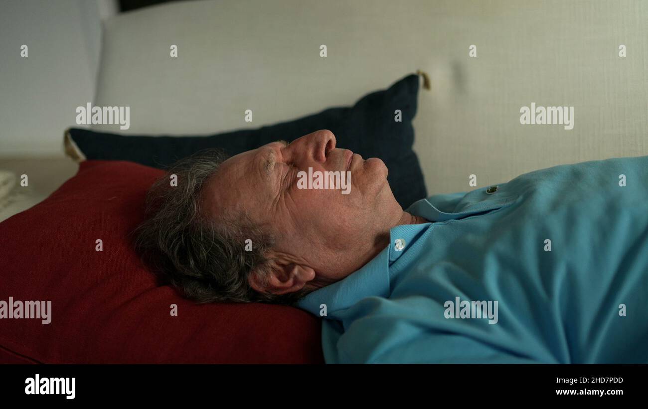Older man lying in sofa resting. Senior person napping Stock Photo - Alamy
