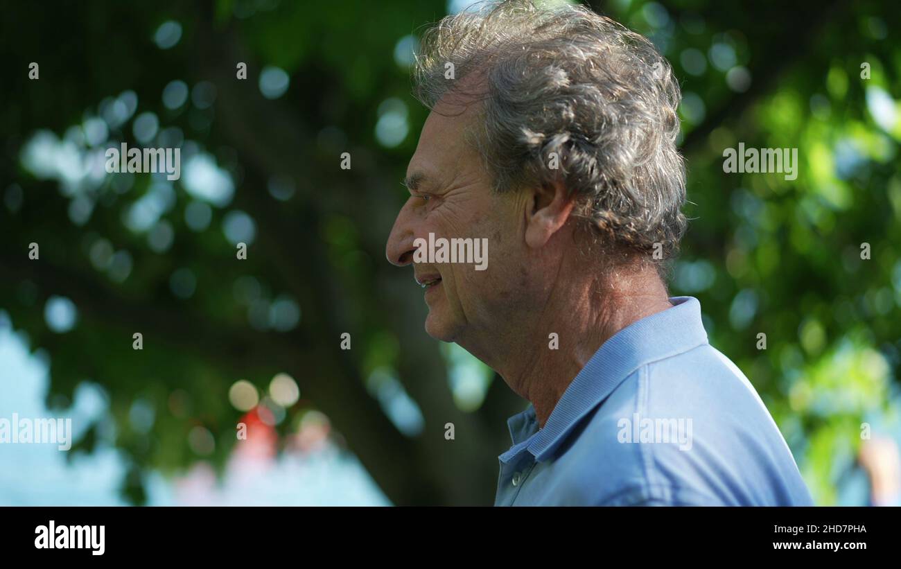 One happy older man walking outside during sunny day, pensive ...