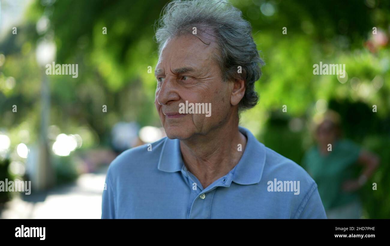 One happy older man walking outside during sunny day, pensive ...