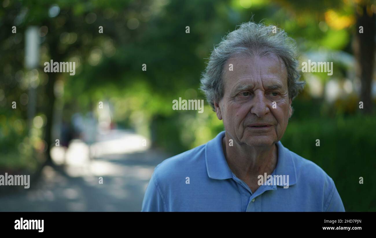 One happy older man walking outside during sunny day, pensive ...