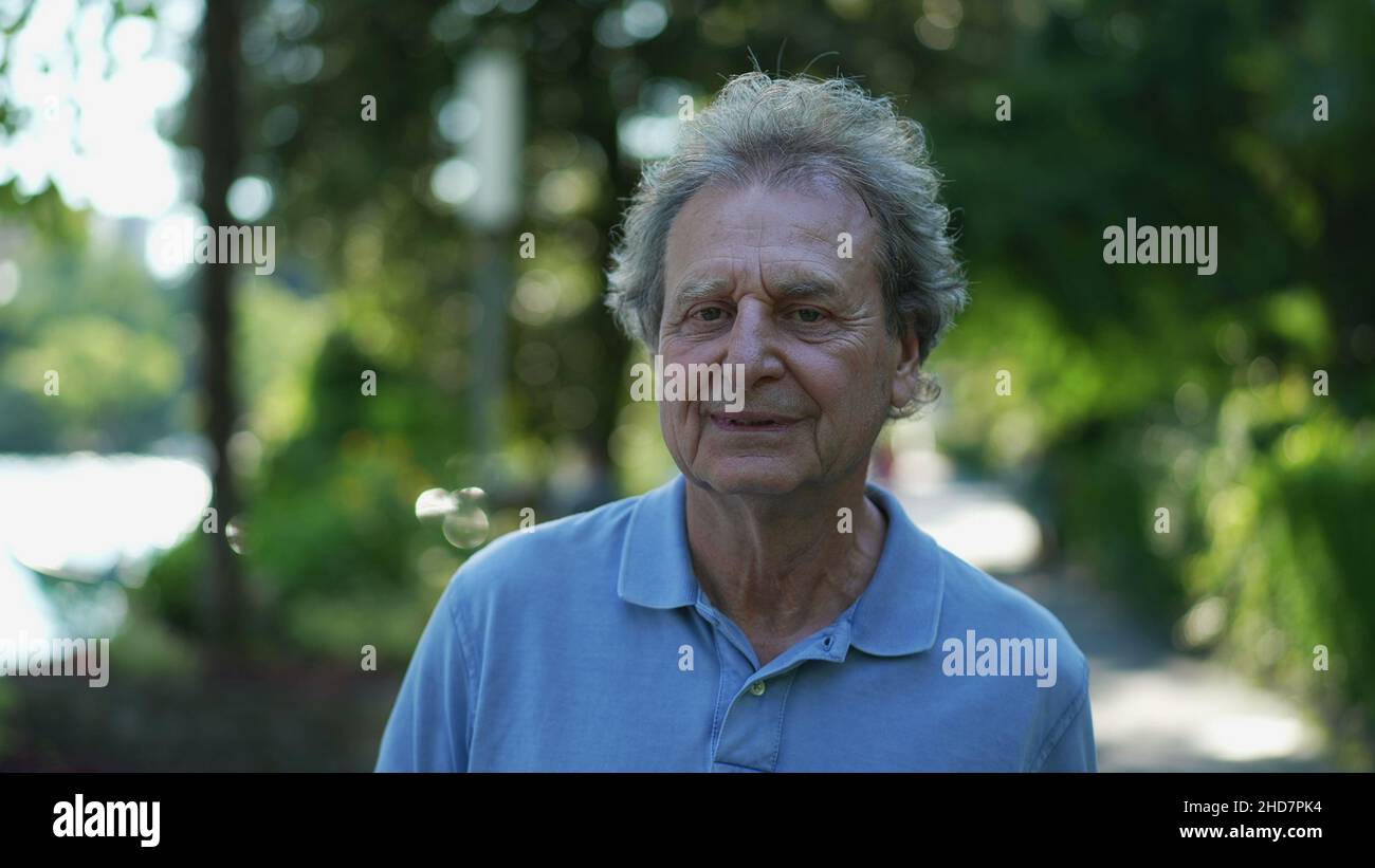 One happy older man walking outside during sunny day, pensive ...