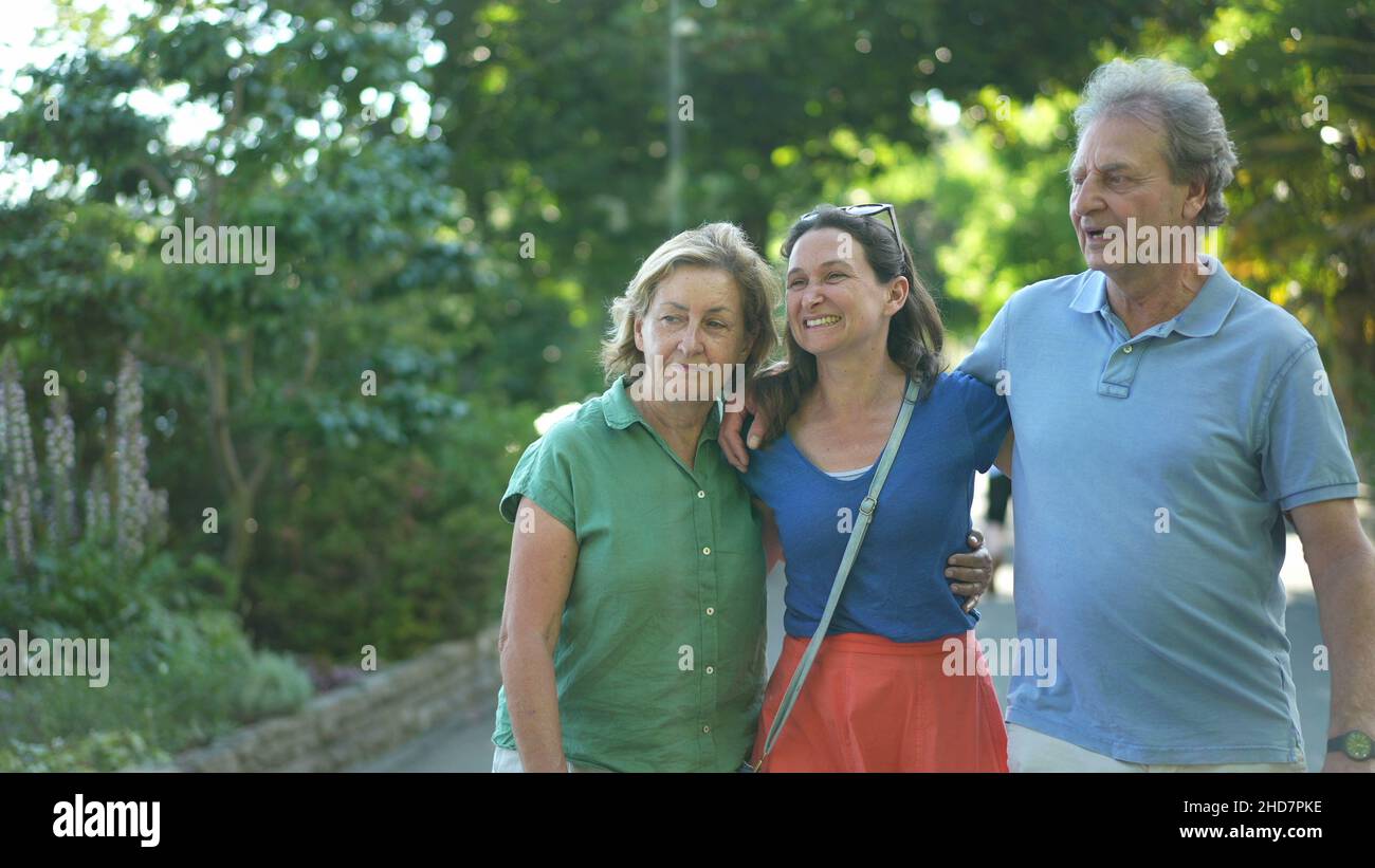 Parents walking with adult daughter together, family day walk outside ...