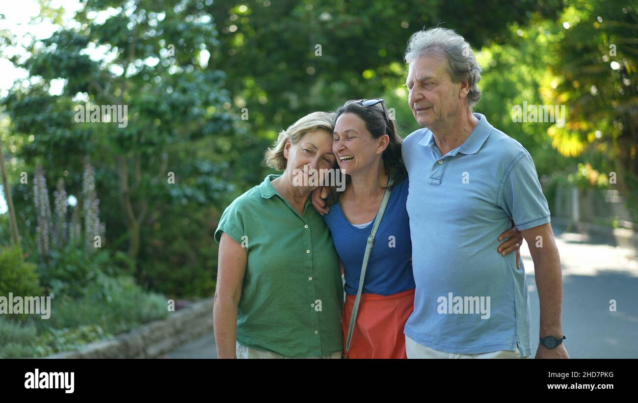 Parents walking with adult daughter together, family day walk outside ...