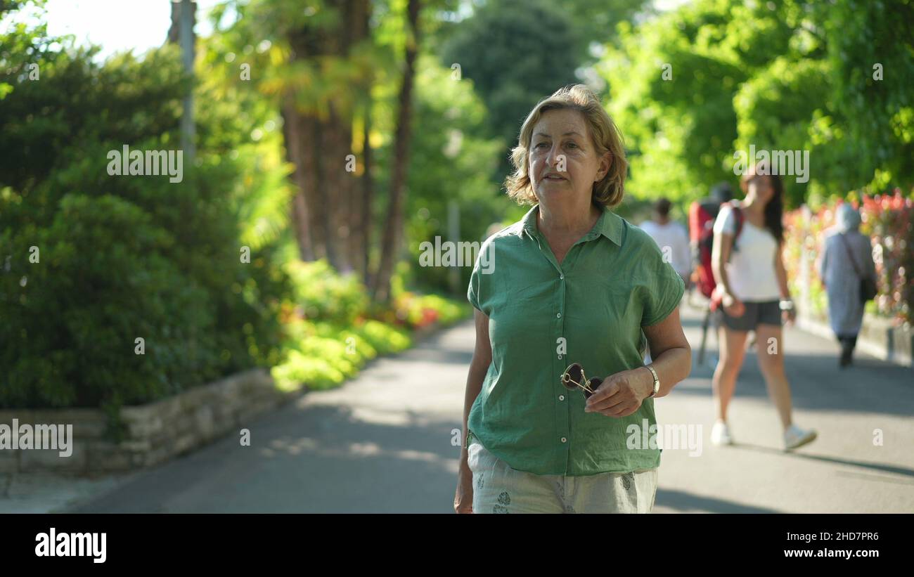 Person walking outside in urban city park, senior lady Stock Photo - Alamy