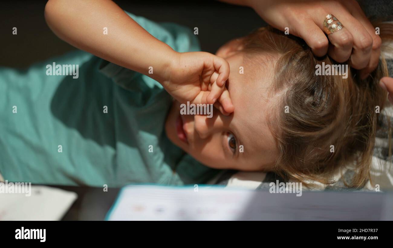 Tired child rubbing eye with hand, mother caressing hair Stock Photo ...