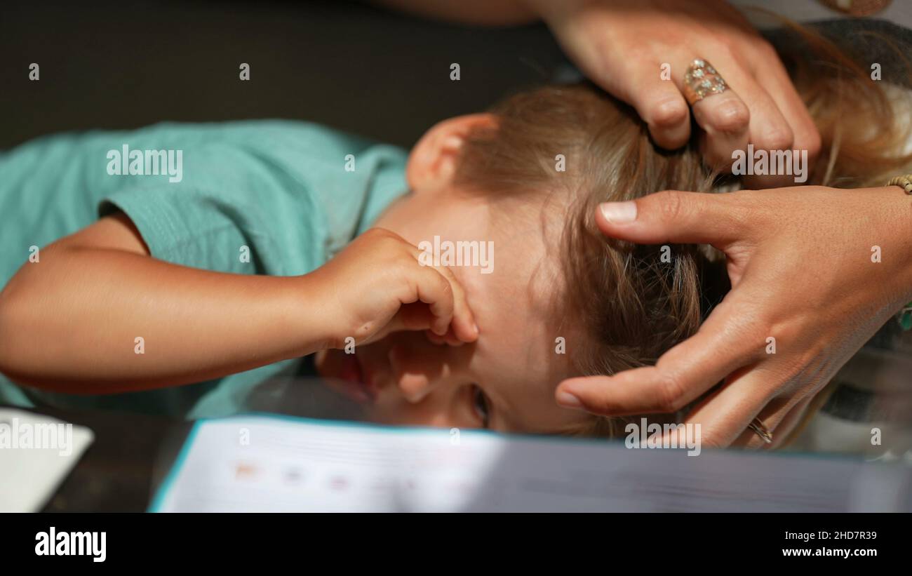 Tired child rubbing eye with hand, mother caressing hair Stock Photo ...