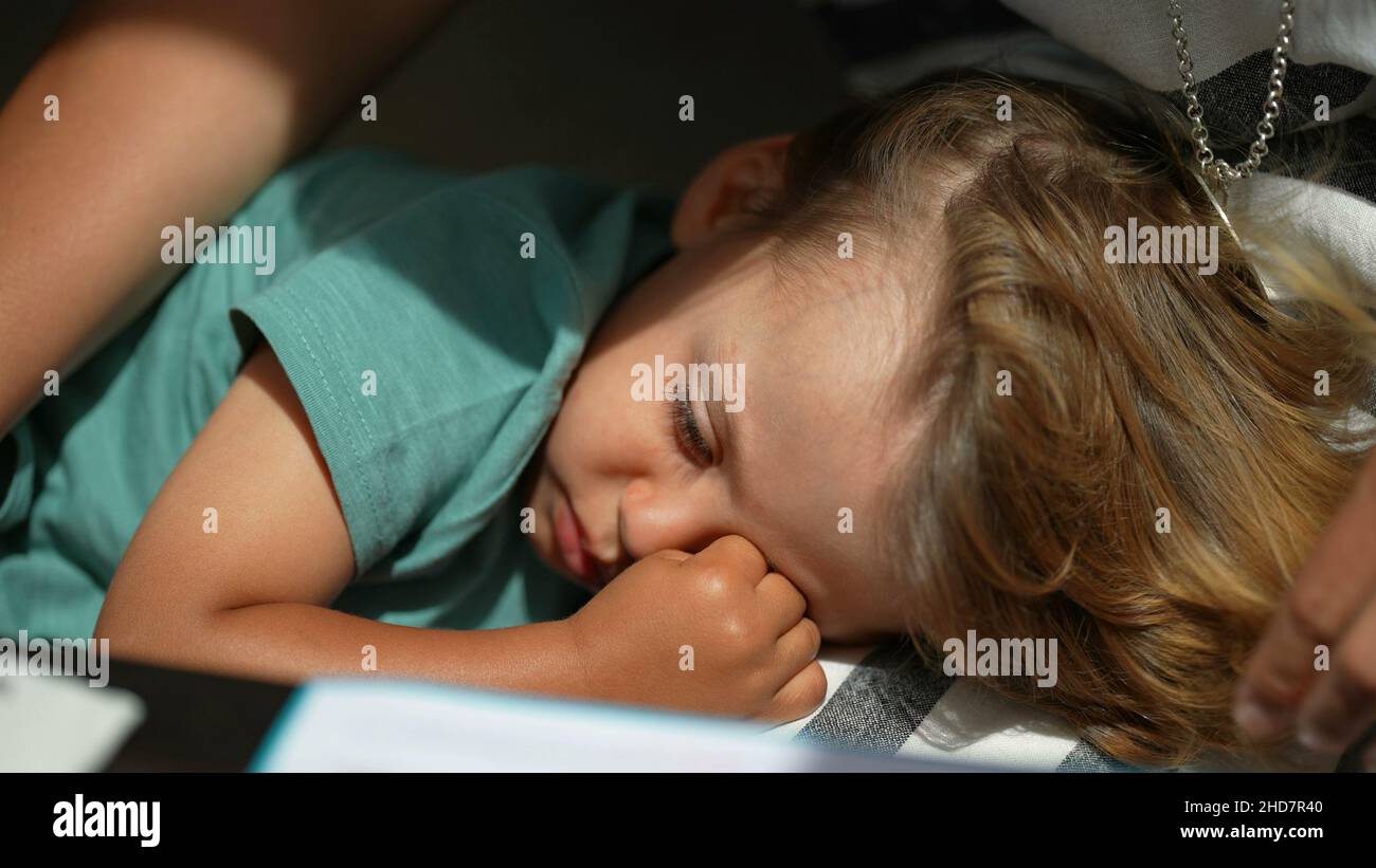 Sleepy child rubbing eye with hand, kid lying down resting Stock Photo ...
