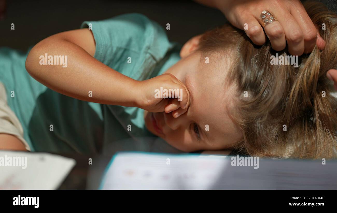Tired child rubbing eye with hand, mother caressing hair Stock Photo ...