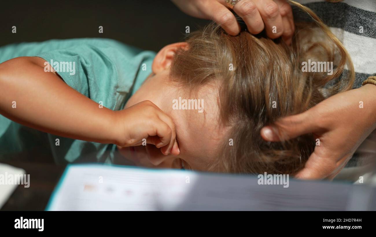 Tired child rubbing eye with hand, mother caressing hair Stock Photo ...