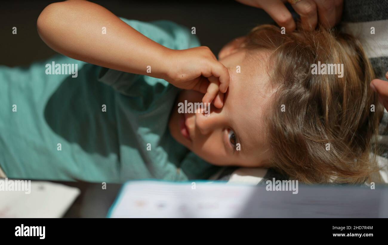 Tired child rubbing eye with hand, mother caressing hair Stock Photo ...