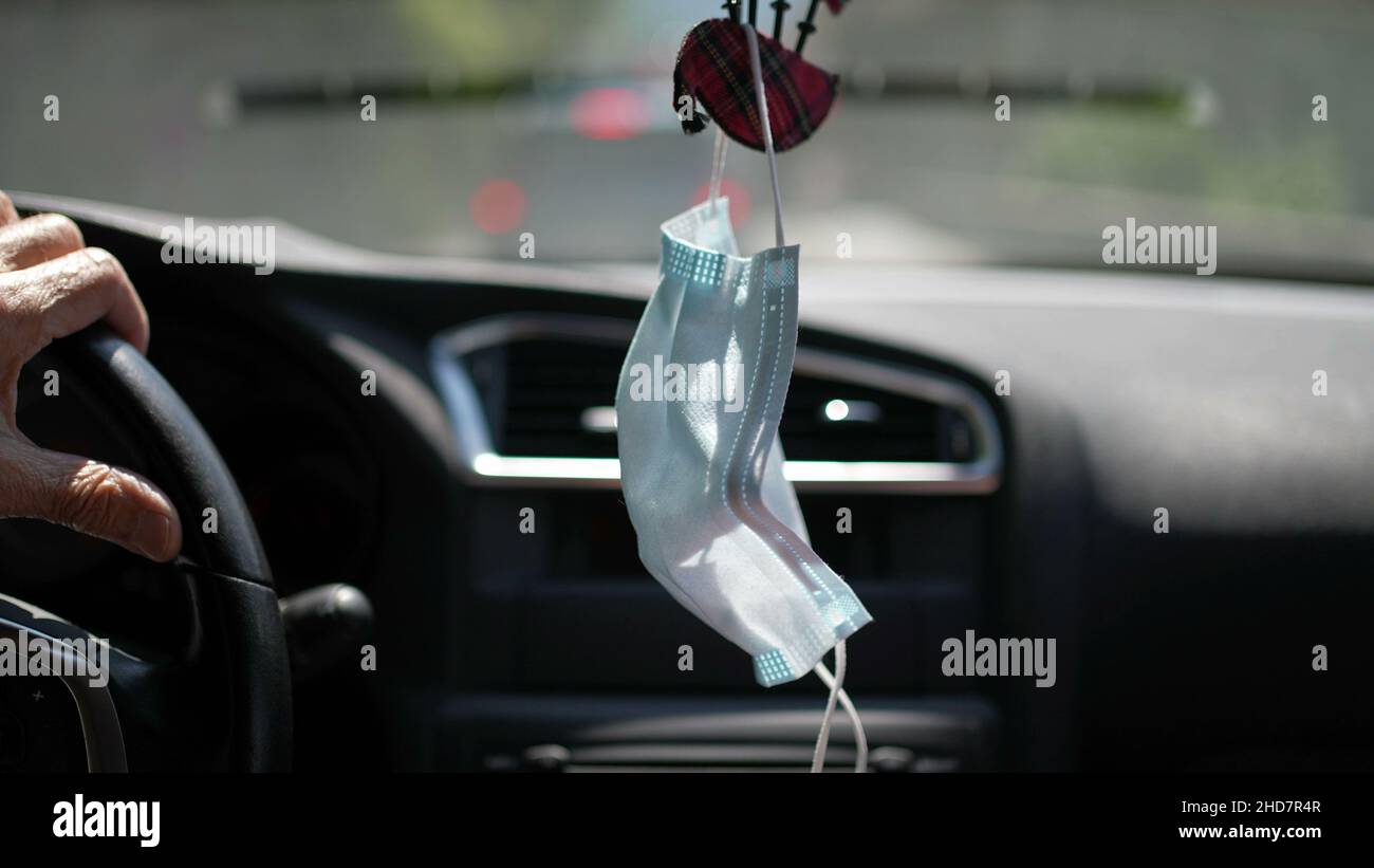 Surgical face mask hanging on car rear-view mirror, covid hangs inside ...