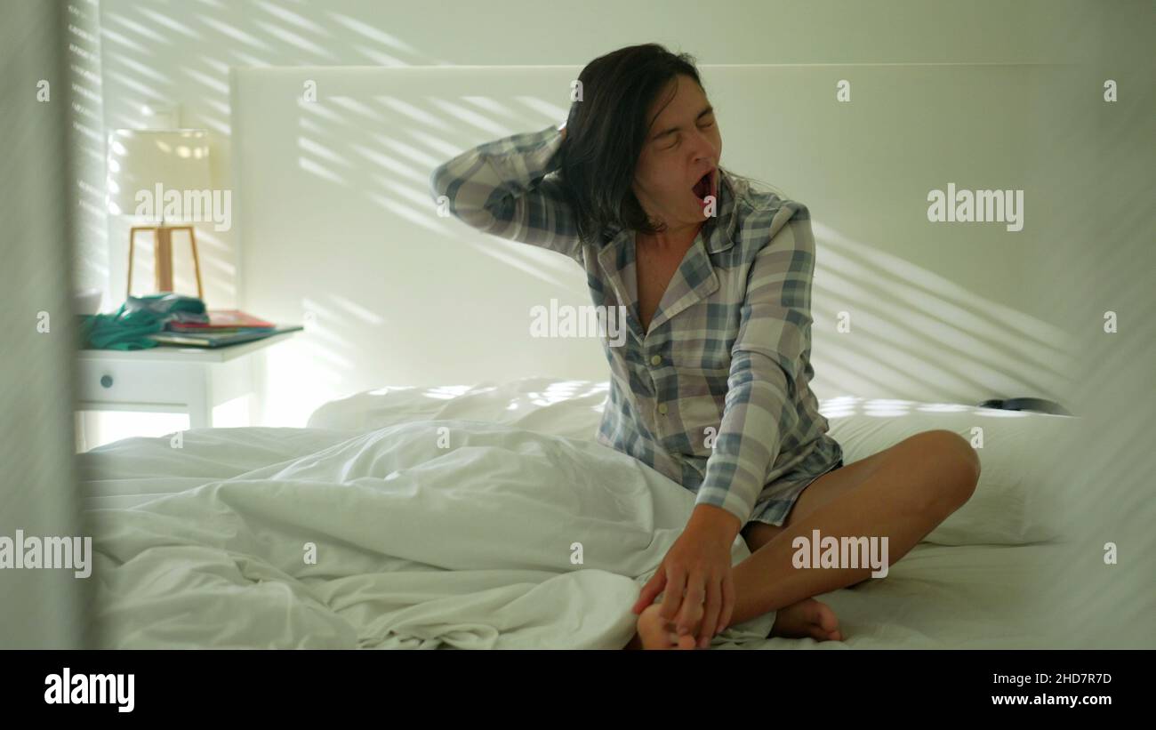 Woman waking up in the morning sitting in bed yawning. Person wake up ...