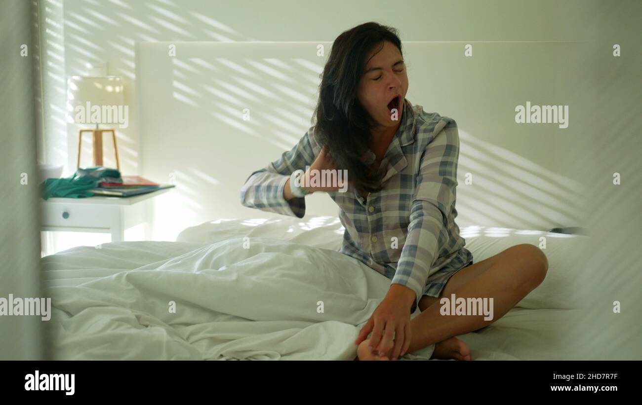 Woman waking up in the morning sitting in bed yawning. Person wake up ...
