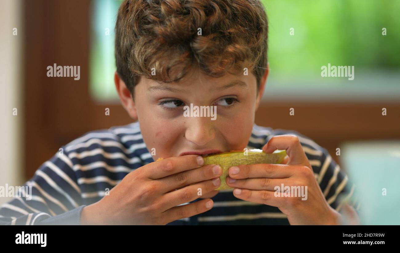 Young boy eating melon fruit. Child eats healthy food Stock Photo - Alamy