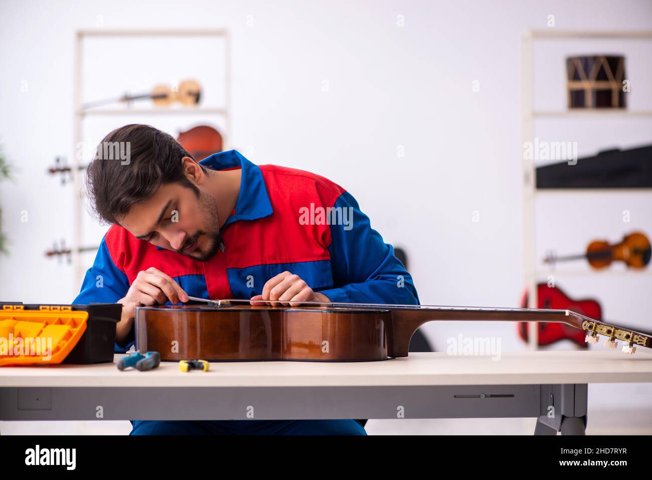 Young repairman repairing musical instruments at workplace Stock Photo ...