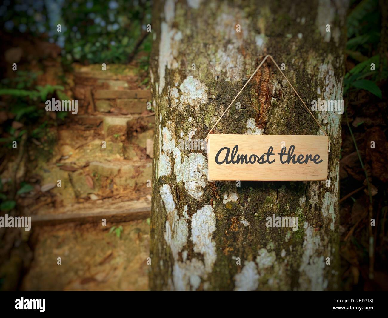 words of encouragement on a small signage - Almost there. Trees and ...