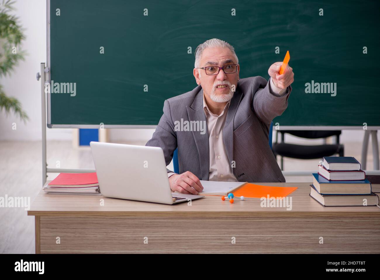 Old teacher holding line in front of blackboard Stock Photo - Alamy