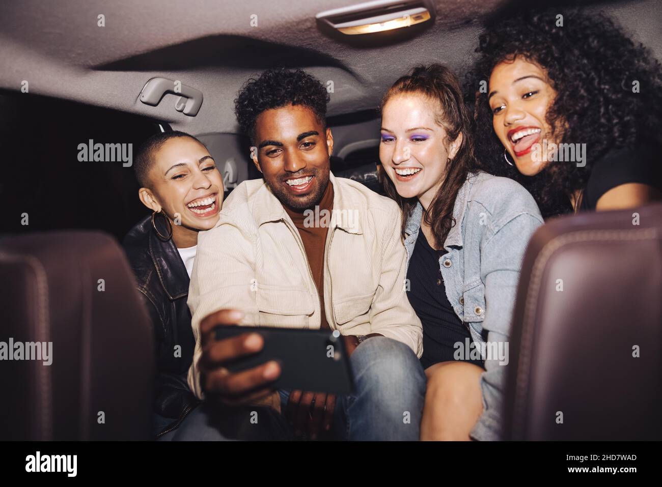 Happy friends taking a selfie together inside a car at night. Group of ...