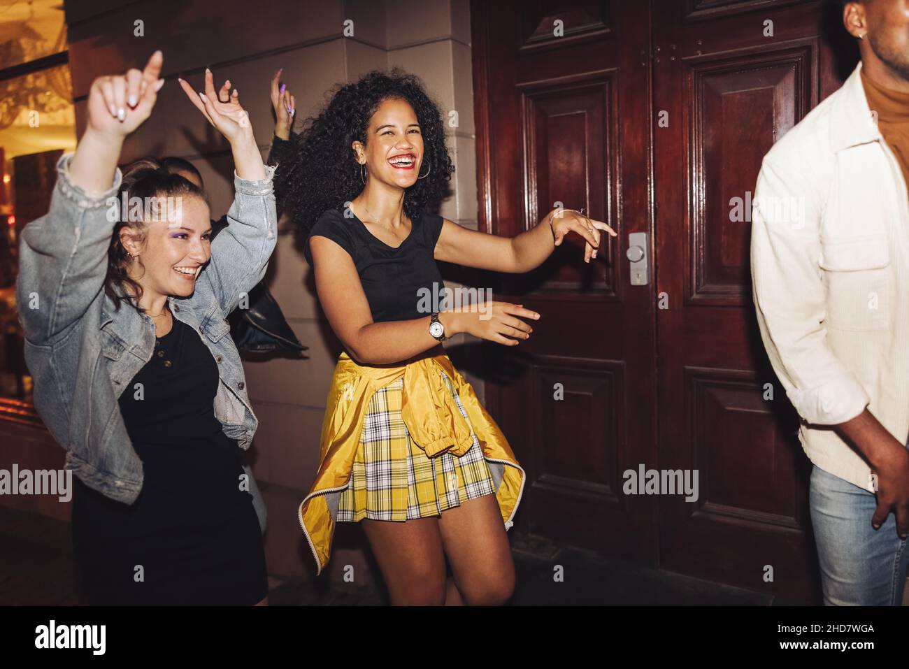 Girlfriends dancing happily in the city at night. Group of vibrant ...