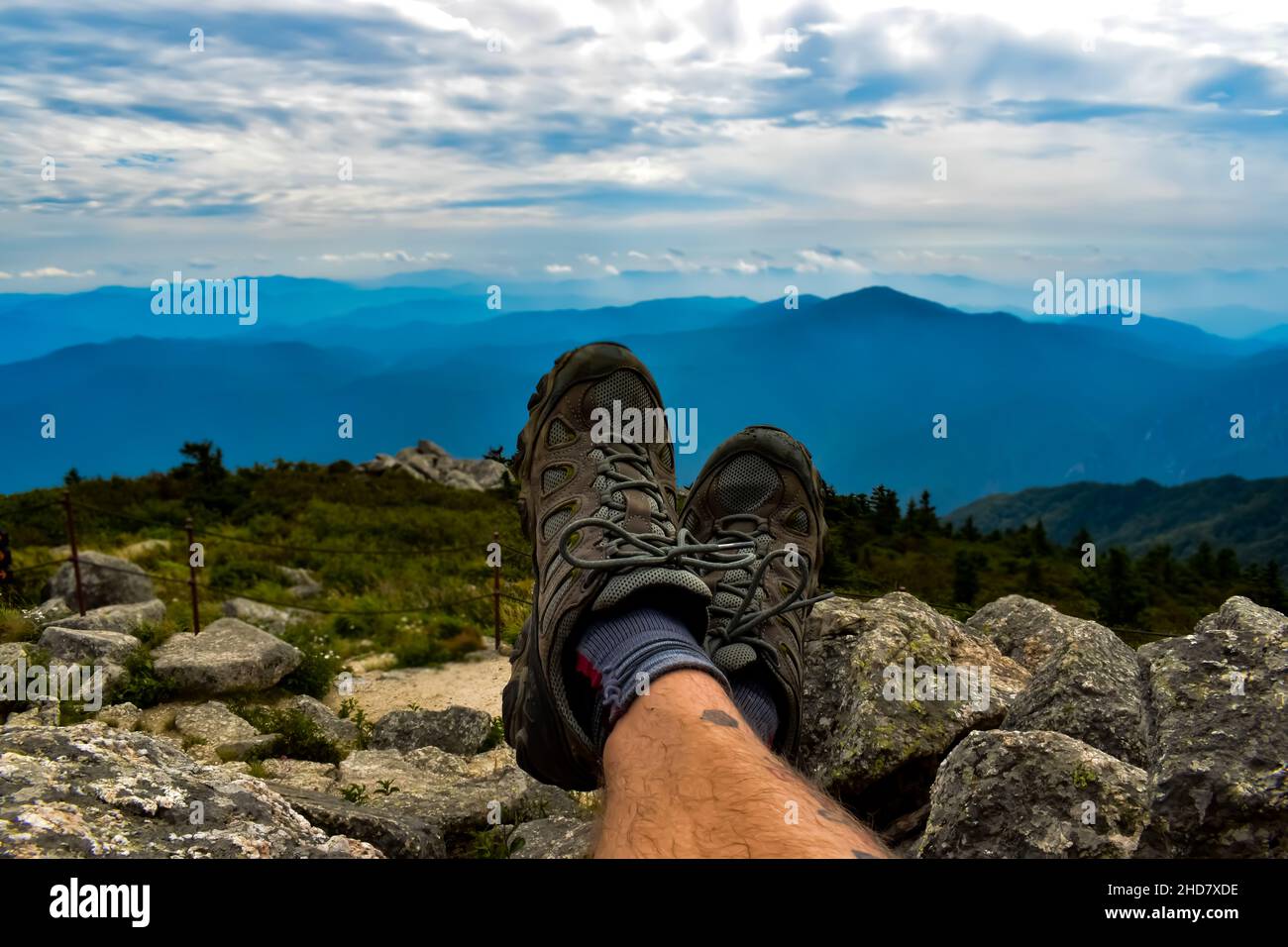 tired legs with hiking boots crossed at the top of a mountain after ...