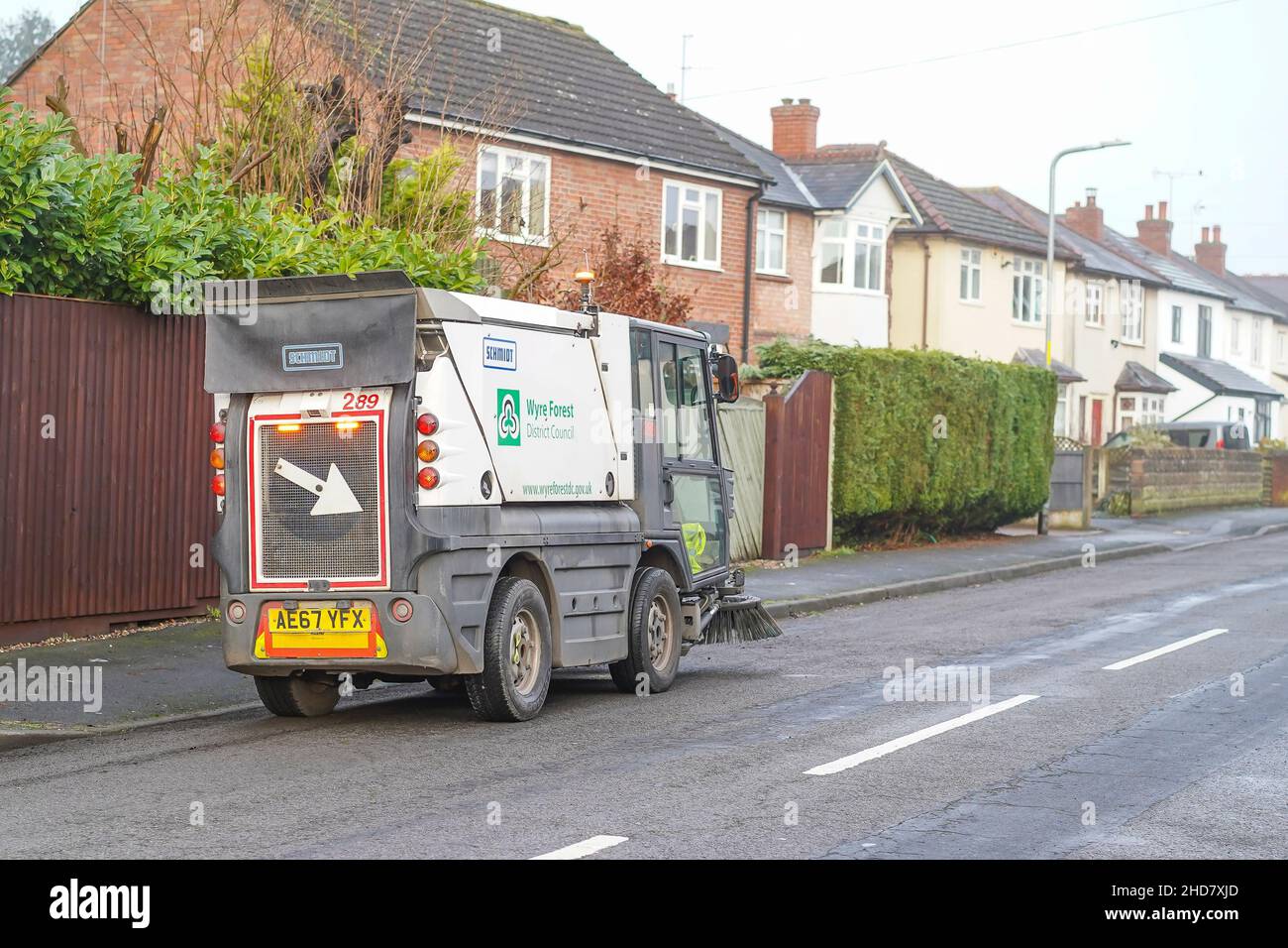 Rear view of council mini road sweeper in operation cleaning the ...