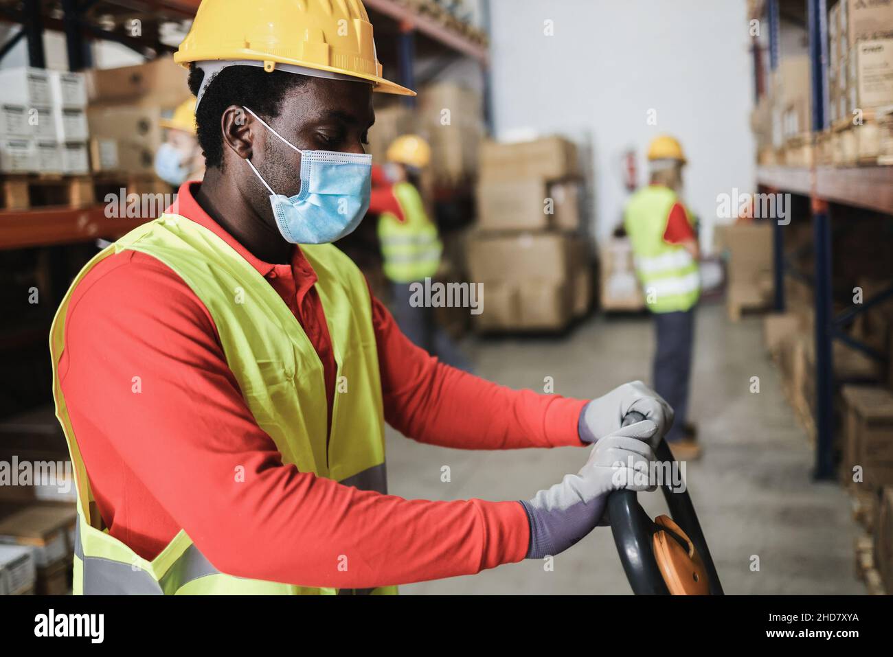 African warehouse worker loading delivery boxes while wearing safety ...