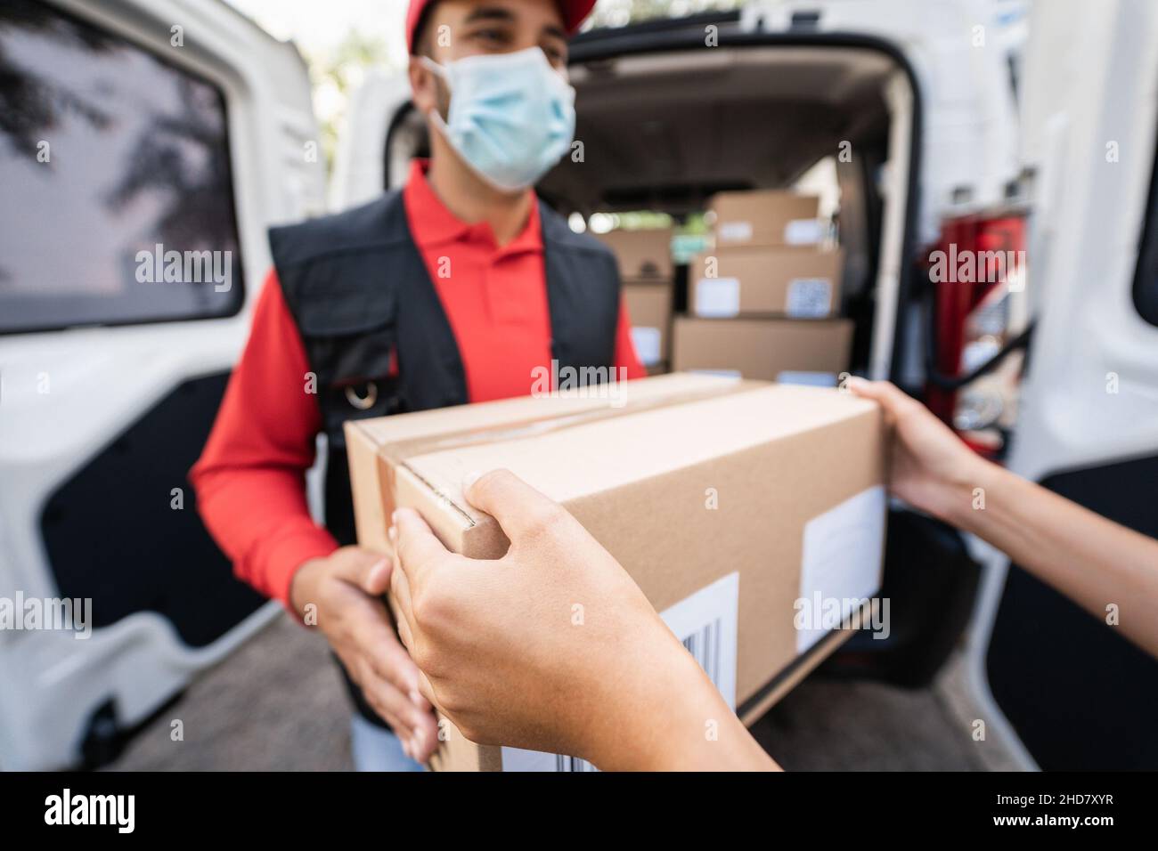 Courier delivering packages with truck while wearing safety mask for ...