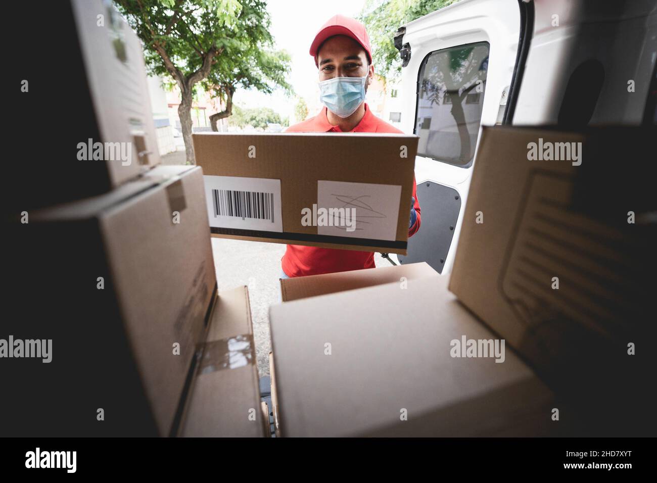 Delivery man picking up box from van while wearing face mask - Focus on ...