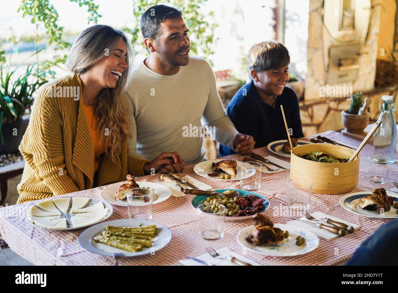 Happy latin family having fun eating together during home dinner ...