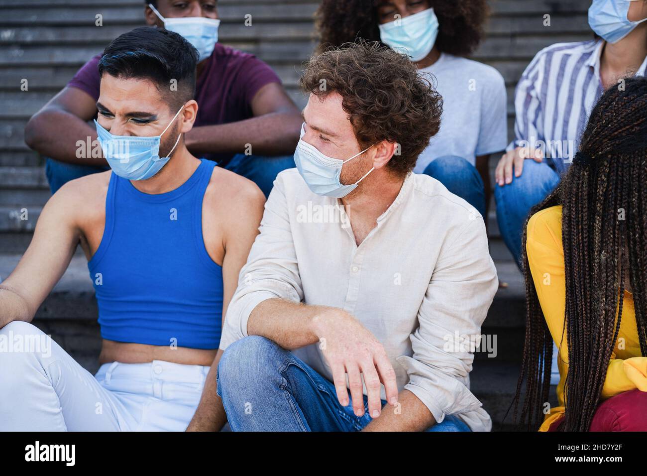 Young diverse people laughing together wearing safety mask outdoor in ...