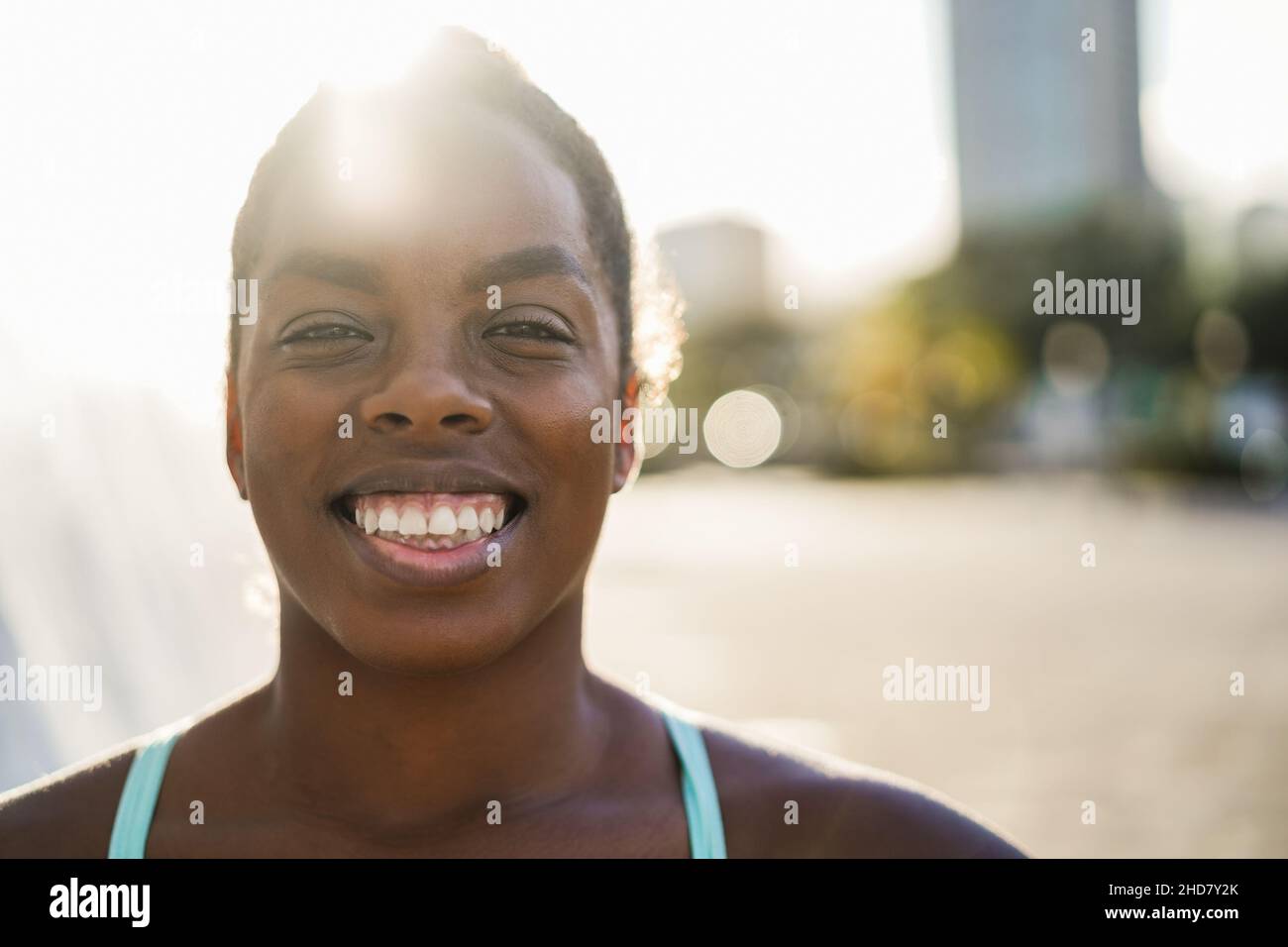Fit african woman smiling on camera with city in background - Focus on ...