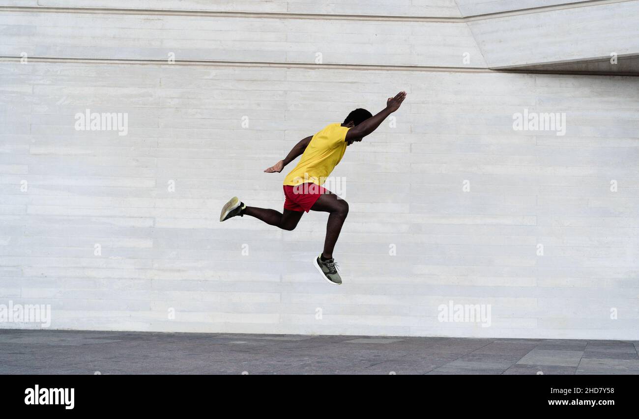 Young black man doing workout routine while running outdoor - Focus on ...