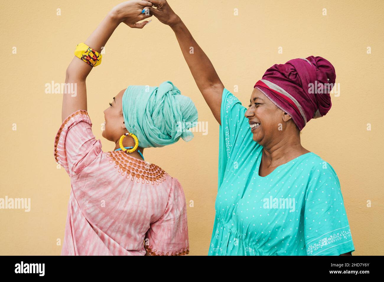 Happy african mother and daughter dancing while wearing traditional ...