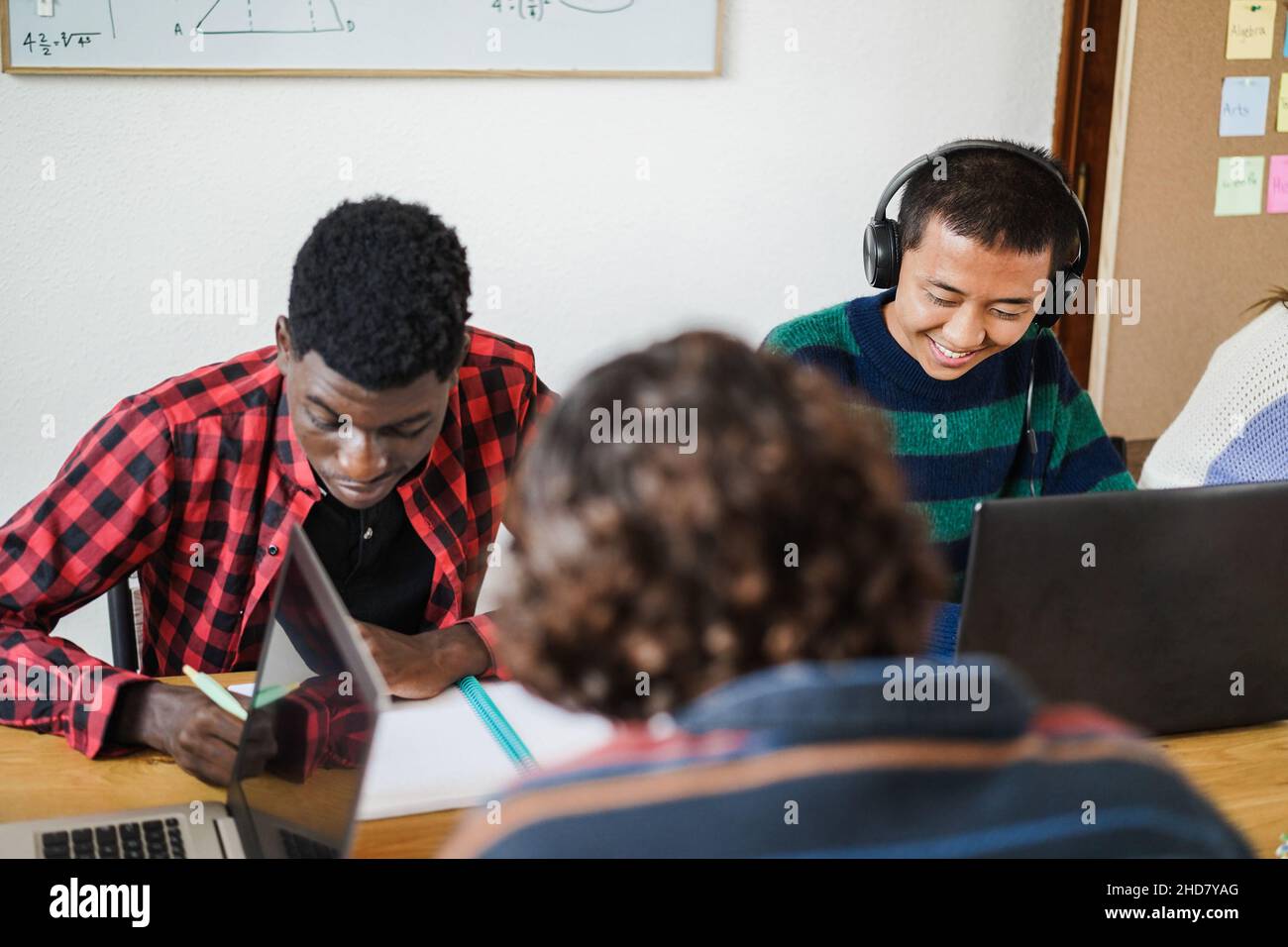 Multiracial students using laptop computers while studying together at ...