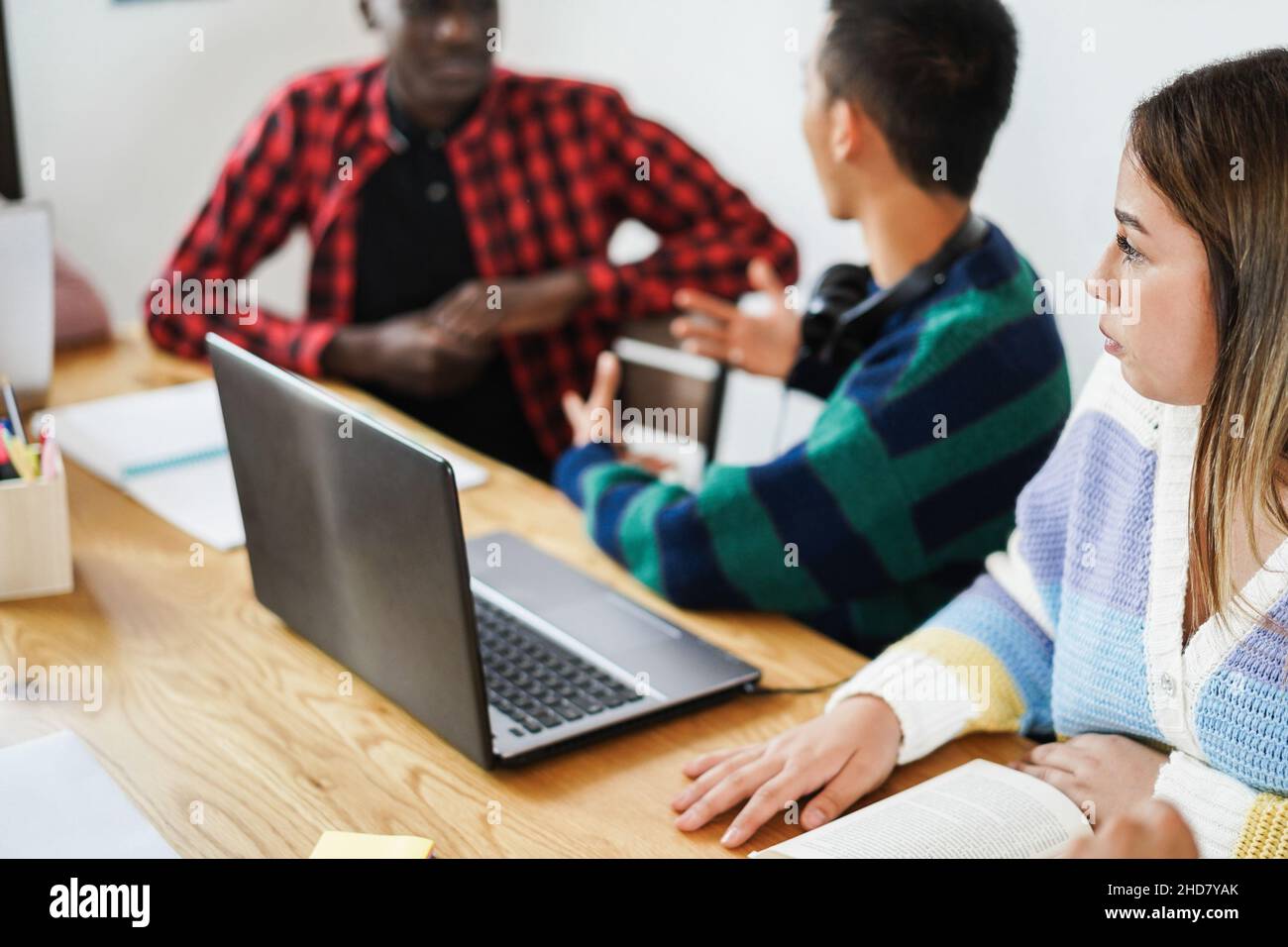 Multiracial students using laptop computers while studying together at ...