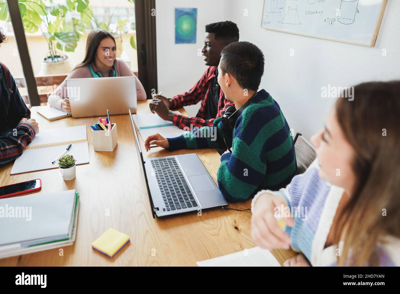 Multiracial students using laptop computers while studying together at ...