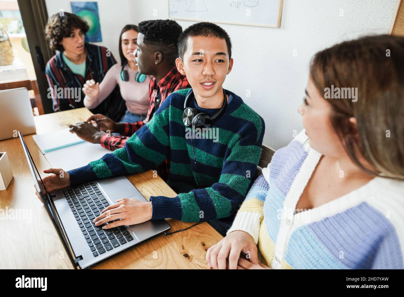 Multiracial students using laptop computers while studying together ...