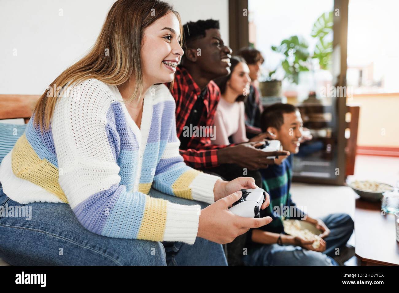 Multiracial young friends having fun playing video games at home ...
