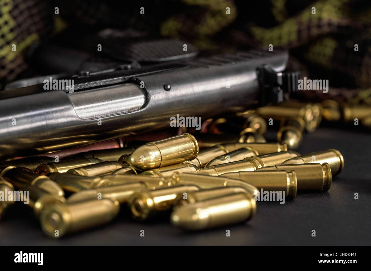 Yellow brass and brown bronze bullets, with black gun near, closeup ...