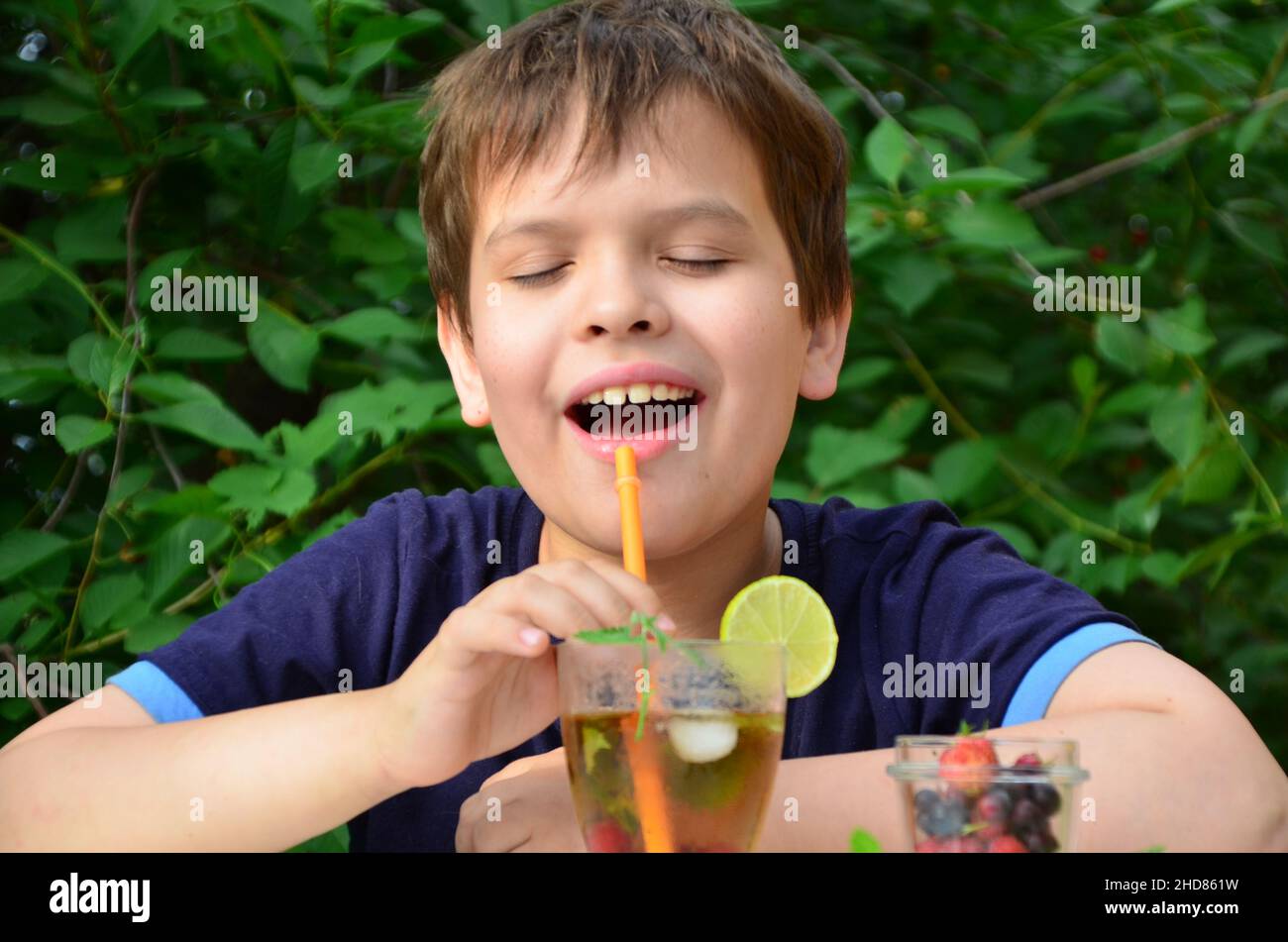 Child boy drinks natural lemonade summer drink, tea with wild berries ...
