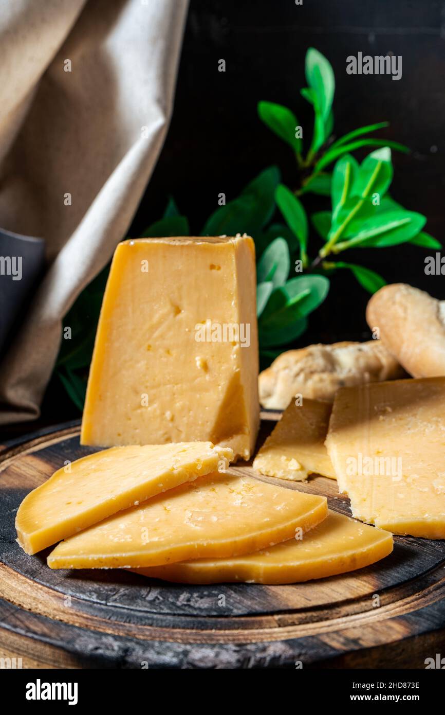 A high view of a piece of provolone cheese cut on a board. Vertical ...