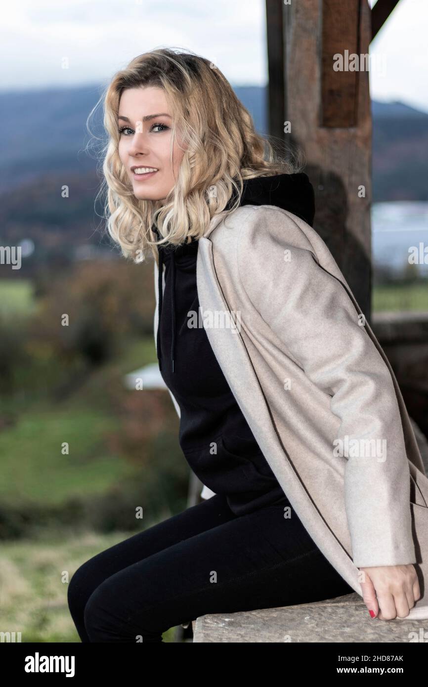 blonde woman sitting on a wall leaning forward Stock Photo - Alamy