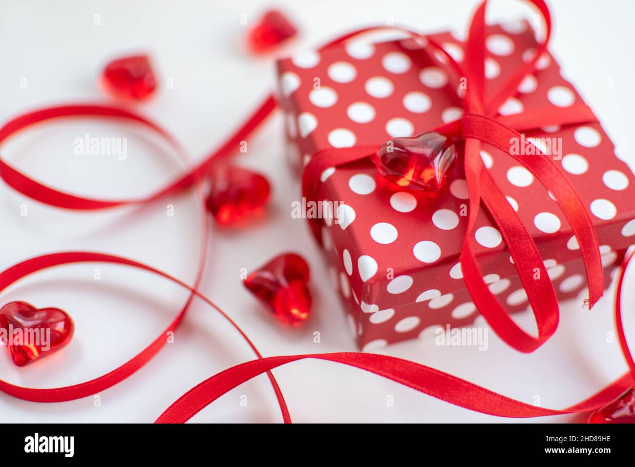 Red gift box with white dots on a white background with bow and ribbon ...