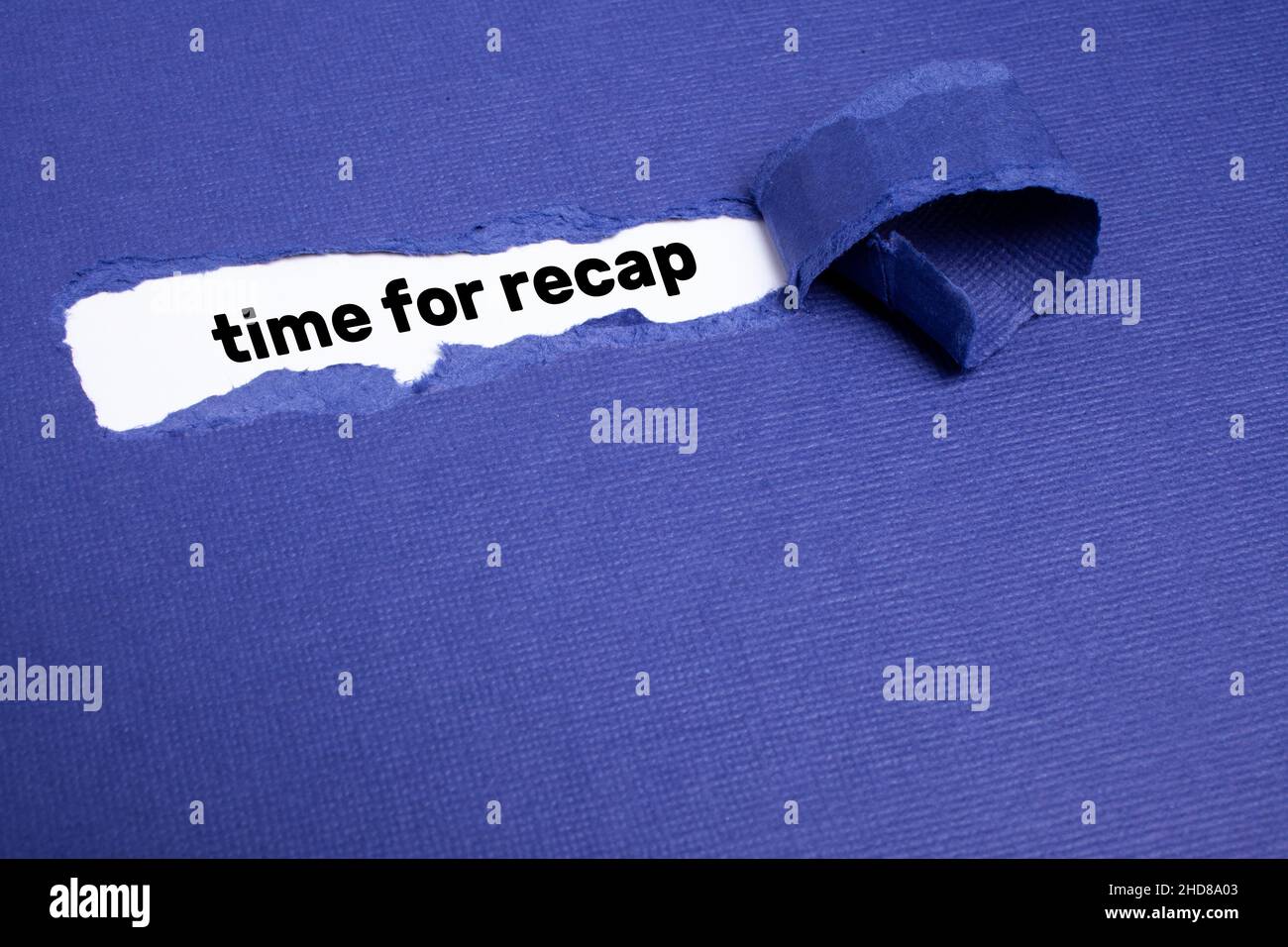 The text TIME FOR RECAP appearing on whitepaper behind torn blue paper ...